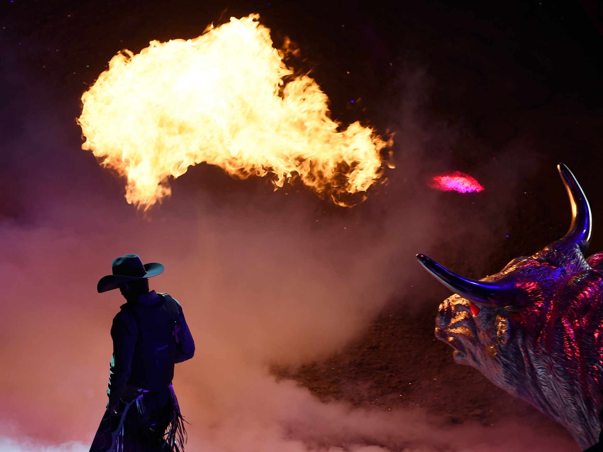 A bull rider introduced with a fire breathing bull statue